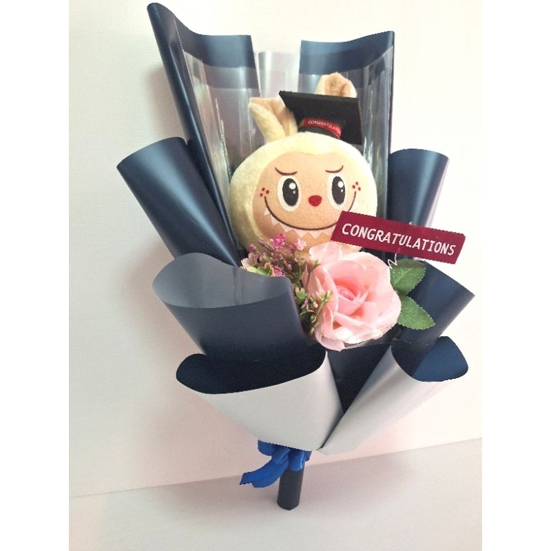 Cream-Colored Labuh Doll Bouquet Holding Pink Rose Wrapped In Blue Can ...